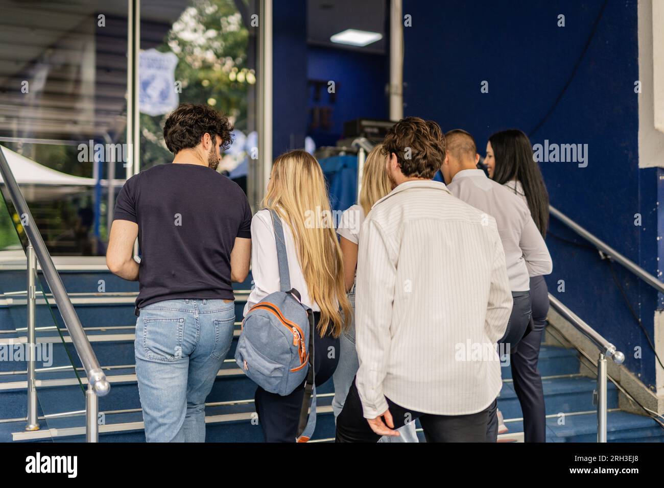 Back view photo of five students walking upstairs, going in college for ...