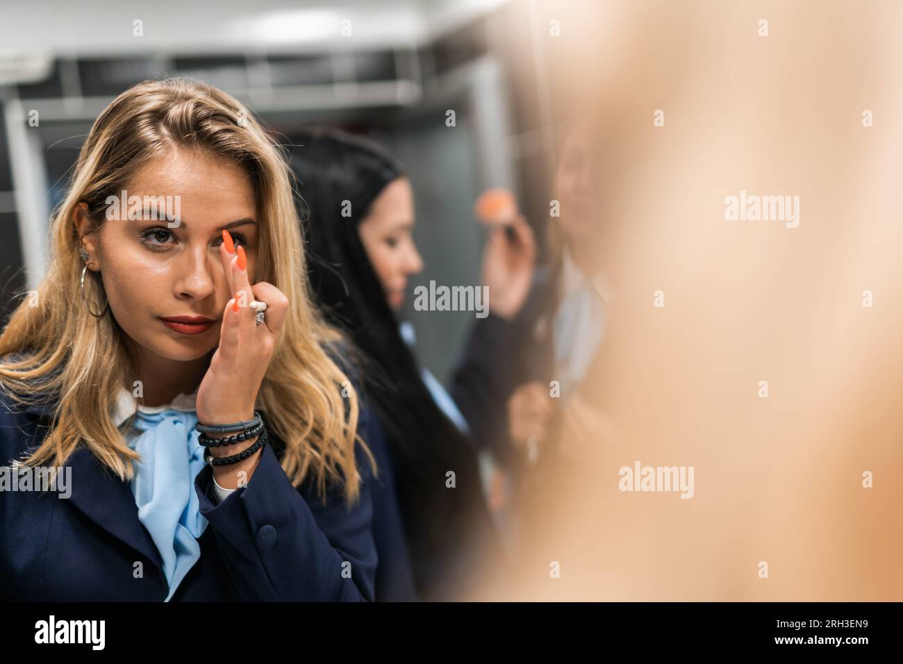 Gorgeous blonde girl correcting eyeshadow at the restroom Stock Photo ...