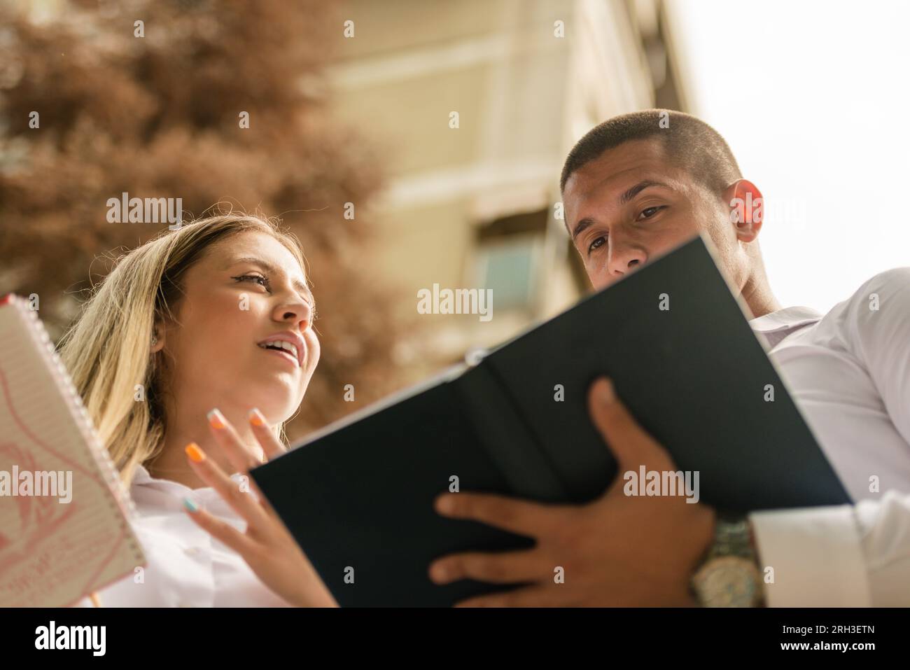 Two young students standing outside with notebooks in their hands and ...