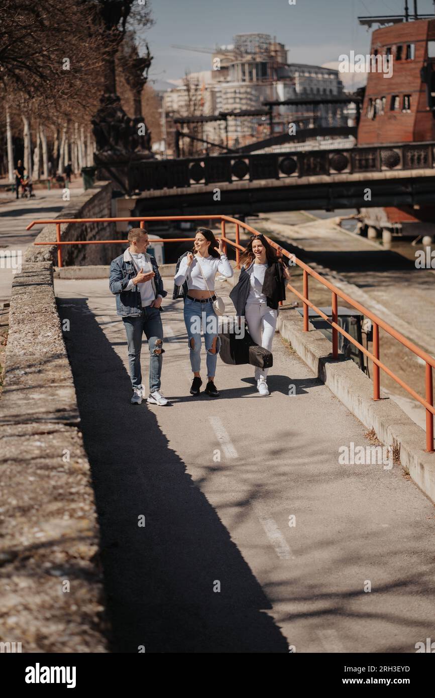 Three best friends walking next to the river at the city and talking ...
