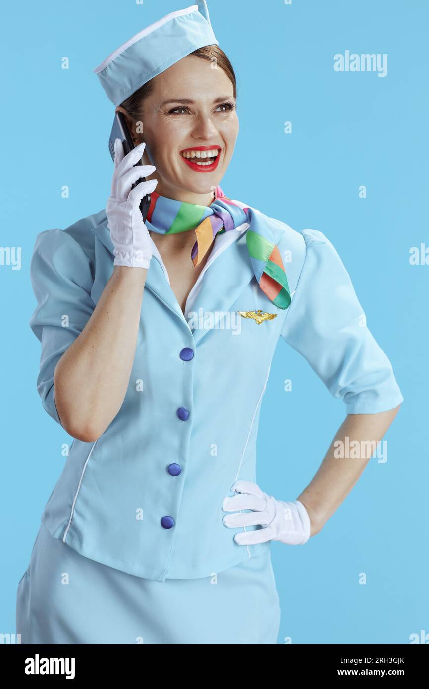 smiling elegant female flight attendant against blue background in blue ...