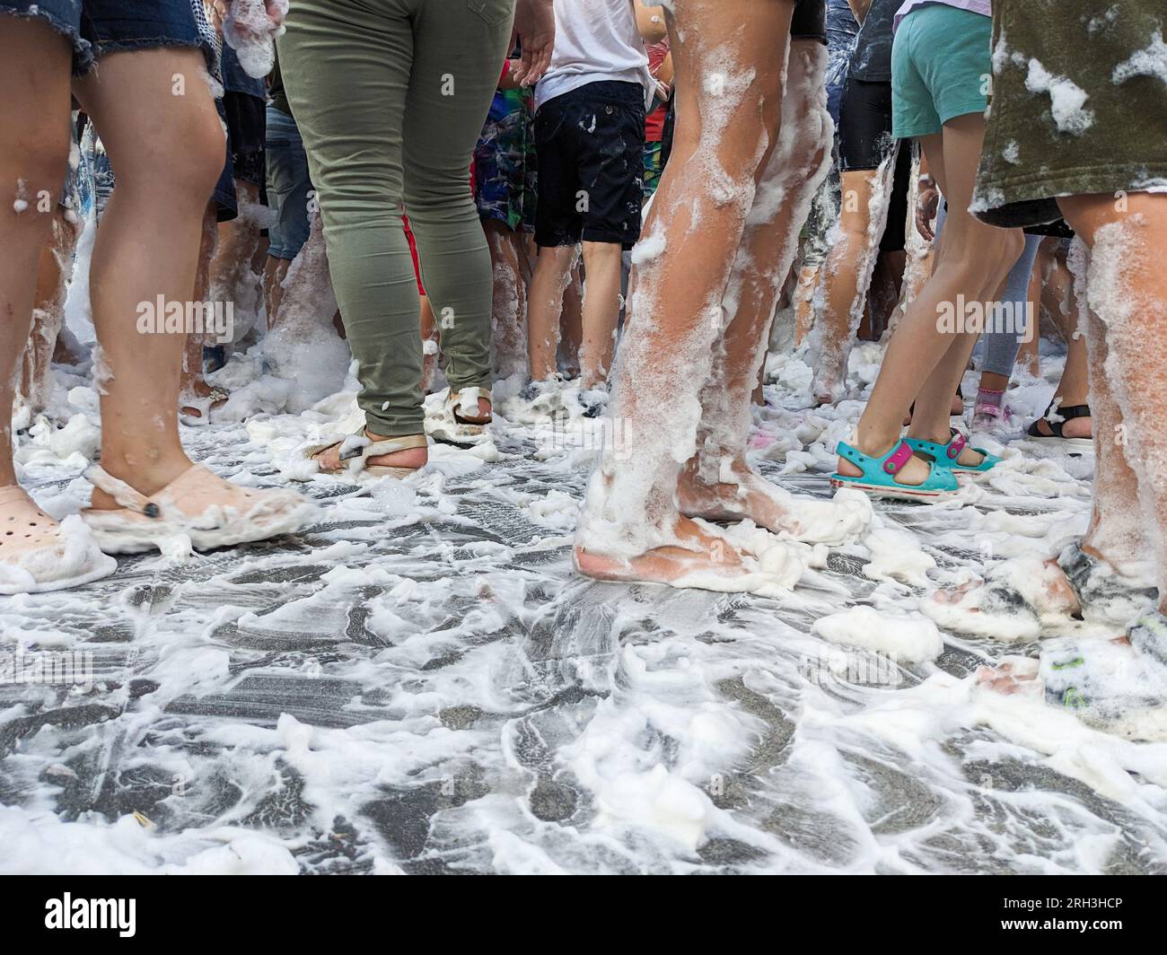 People at a foam party in summer, feet close-up, a lot of foam in the ...