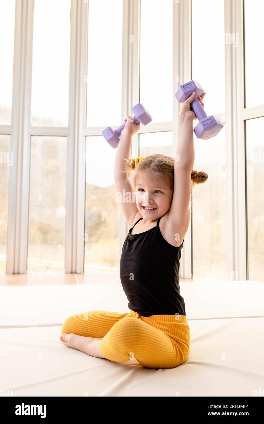 Little blonde girl lifting dumbbells, having fun Stock Photo - Alamy