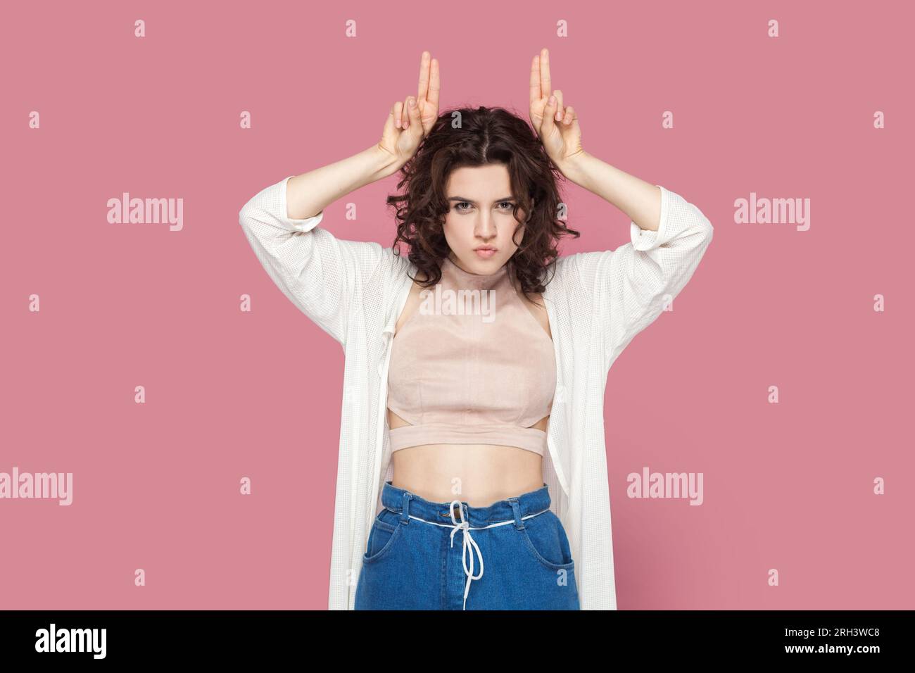 Portrait of angry aggressive attractive woman with curly hair wearing ...