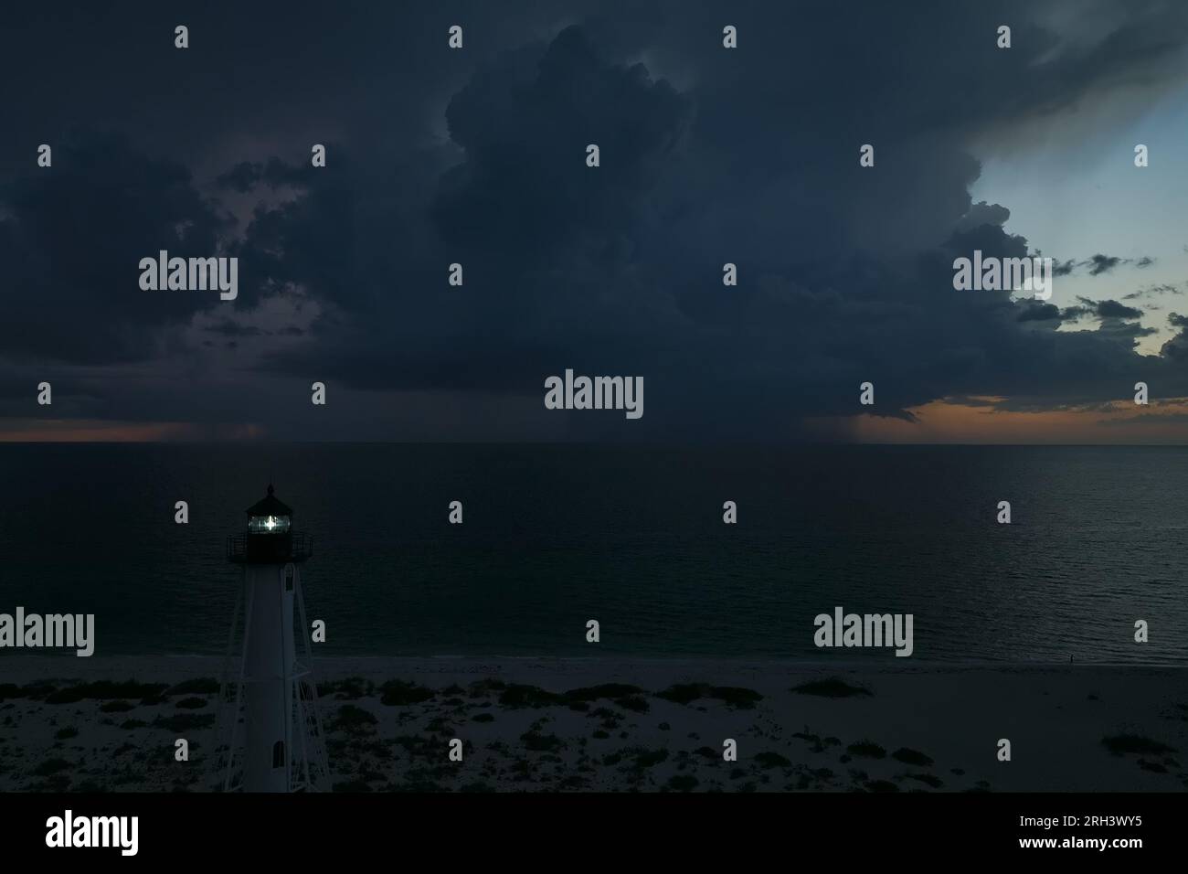 White tall lighthouse on sea shore with blinking light at stormy night ...