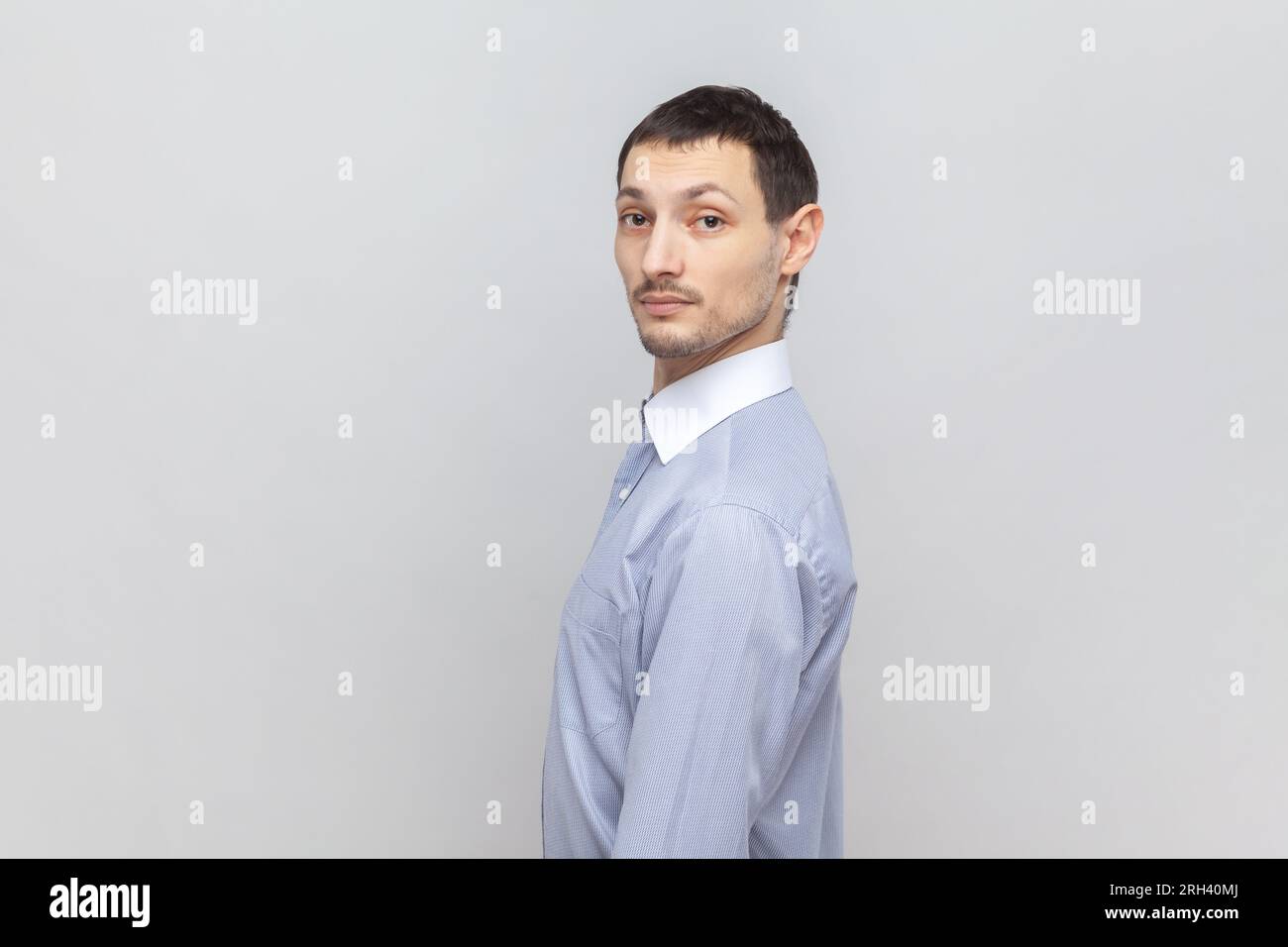 Side view portrait of serious attractive man standing looking at camera ...