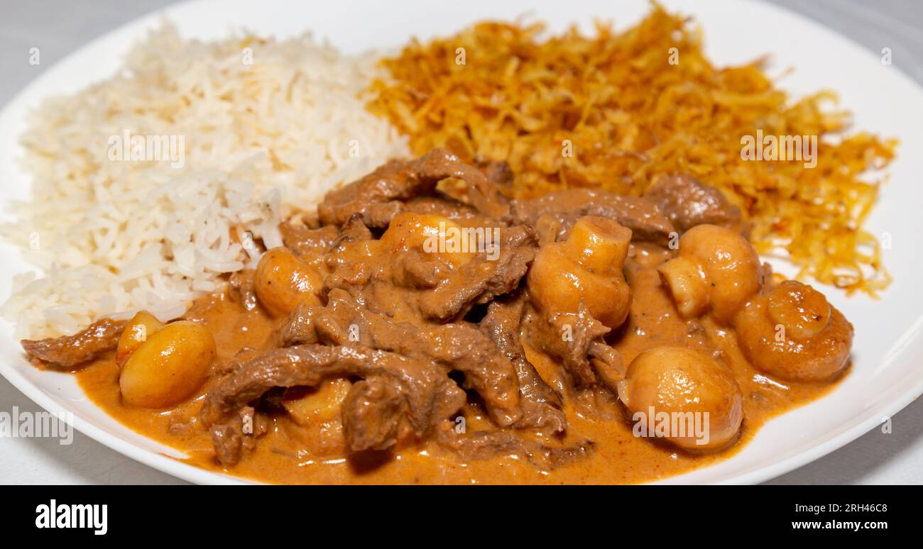 Traditional filet mignon stroganoff served on a white plate with rice ...