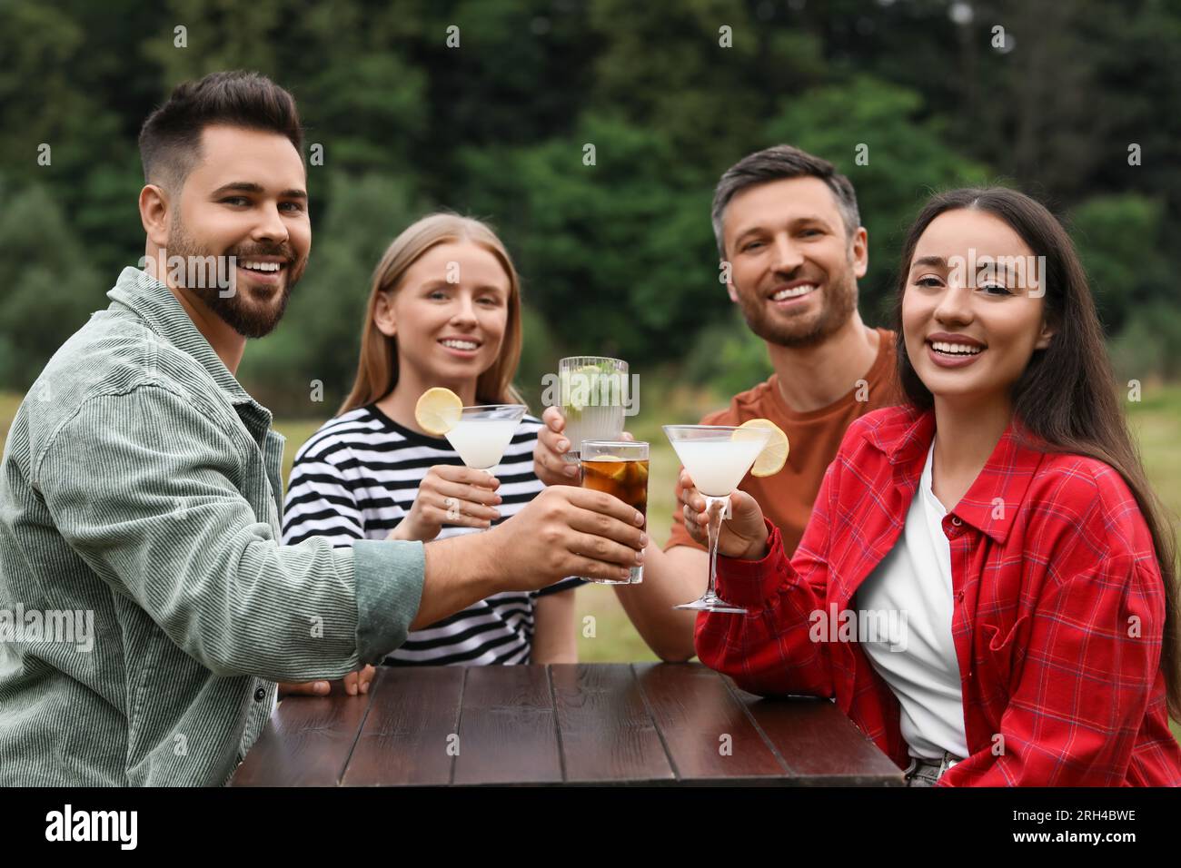 Happy friends holding glasses with cocktails at table outdoors Stock ...