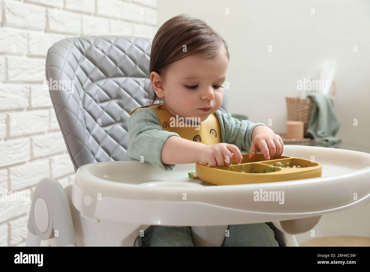 Cute little baby eating healthy food in high chair indoors Stock Photo ...