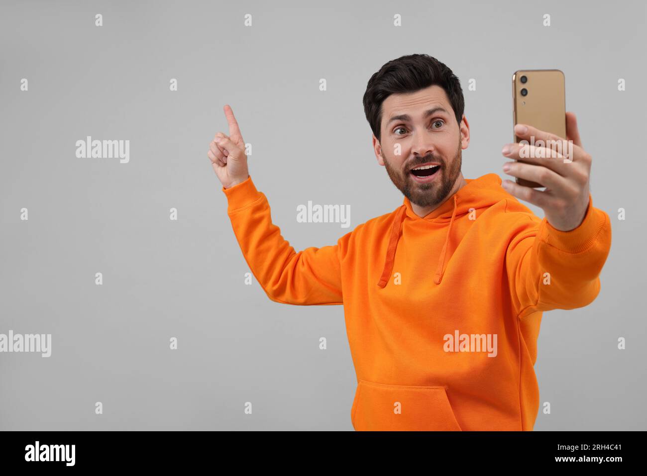 Emotional man taking selfie with smartphone on grey background, space ...