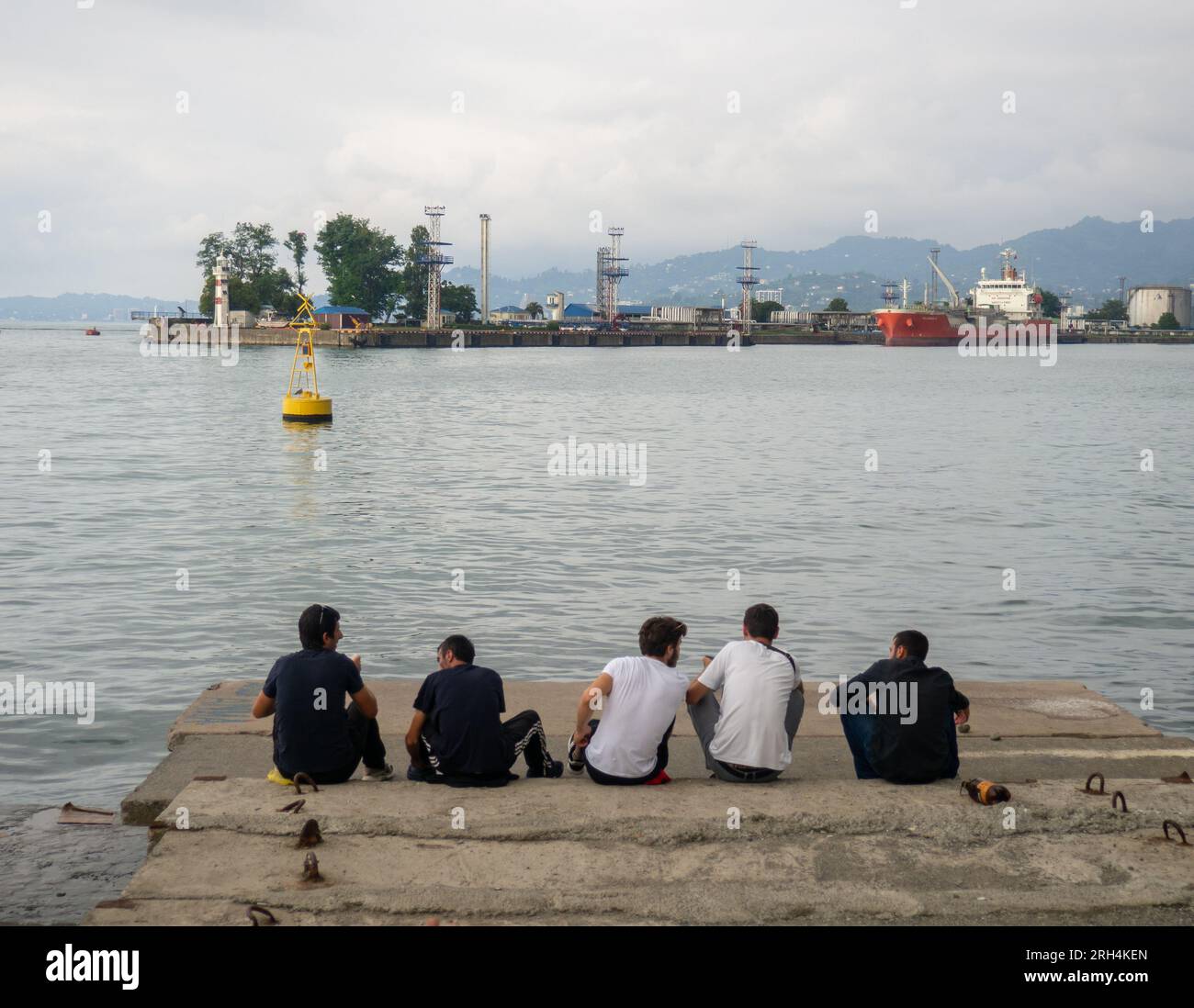 The men are sitting on the pier with their backs to the camera. Rest in ...
