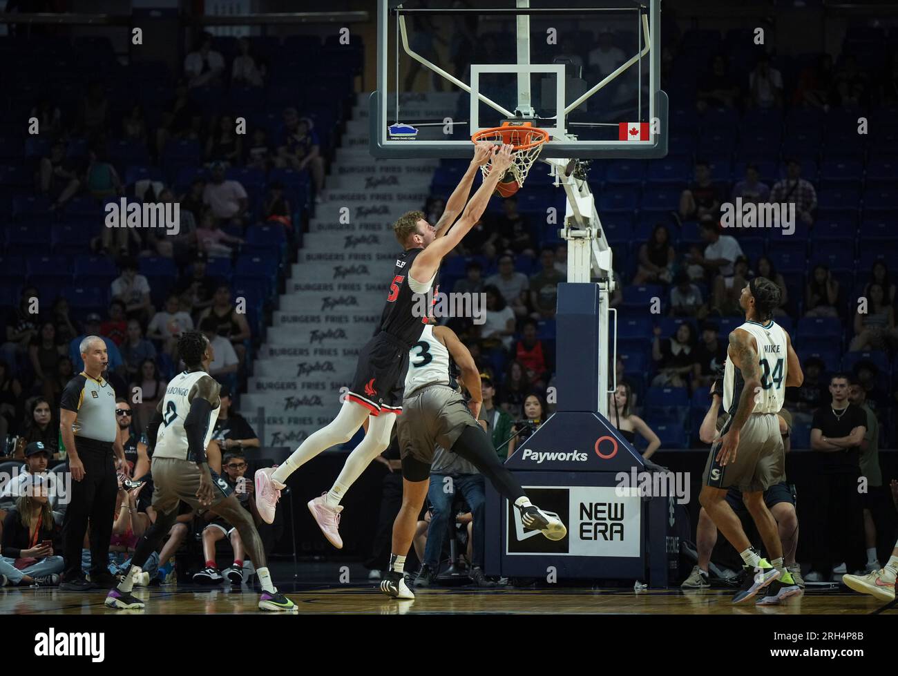 Calgary Surge's Kylor Kelley, center, dunks over Scarborough Shooting Stars' Elijah Lufile ...