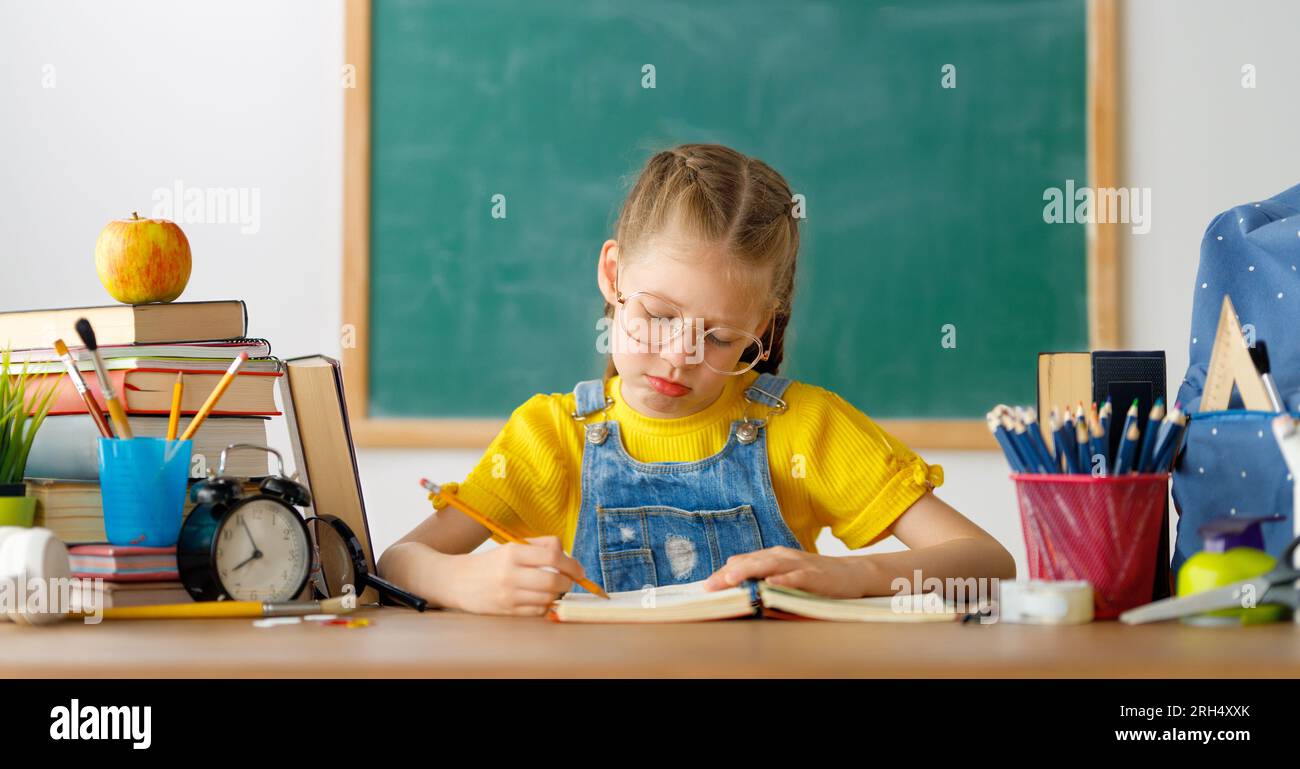 Back to school. Thinking child is sitting at desk. Girl doing homework ...