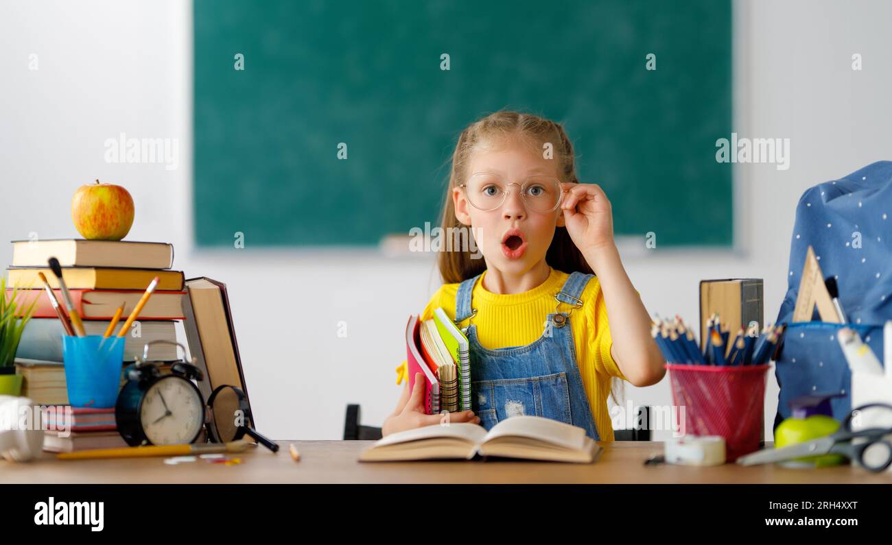 Back to school! Happy cute industrious child is sitting at a desk ...