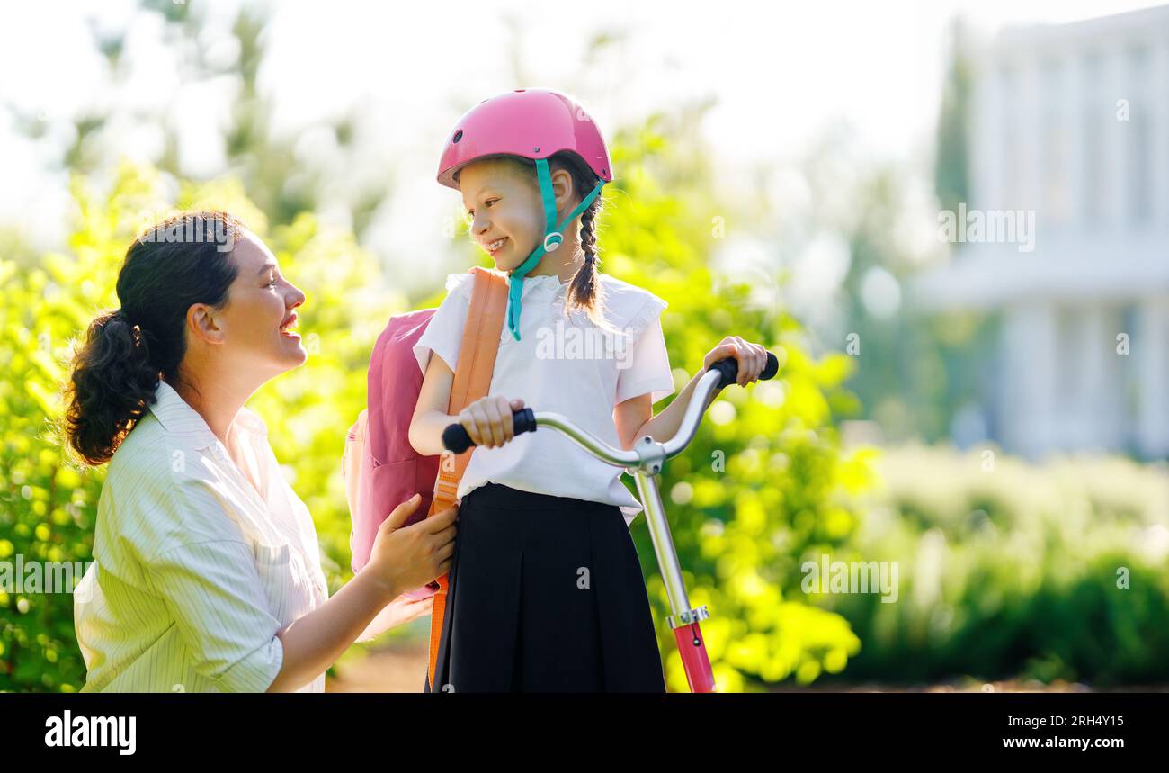 Girl in safety helmet with bike and backpack. Happy child with mother ...