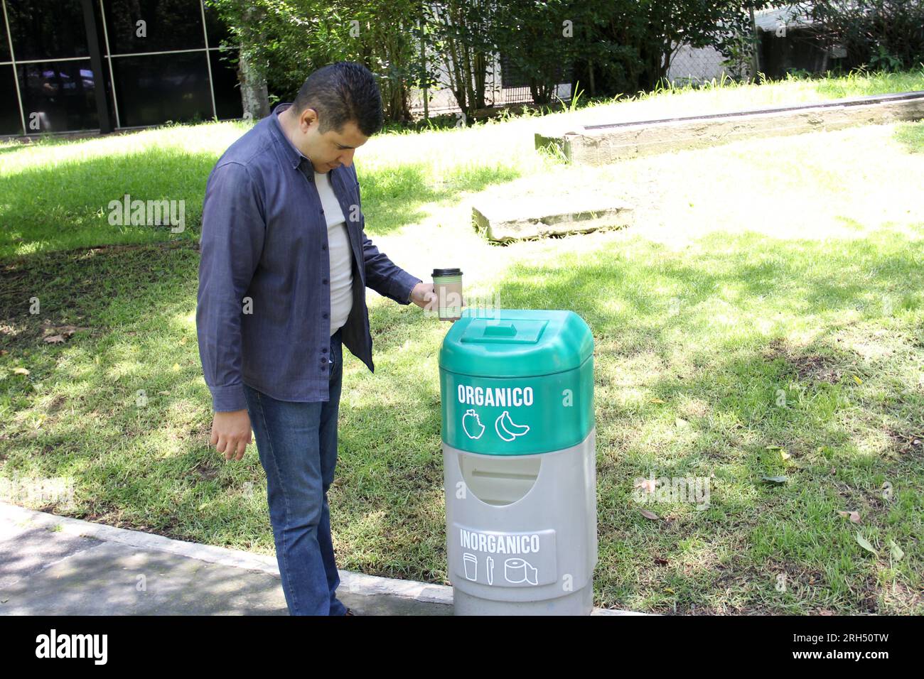 Dark-haired Latino adult man throws his carton cup of coffee into a ...