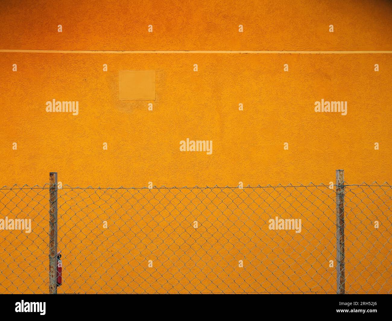 Chain link fence pattern against vibrant yellow wall as background ...