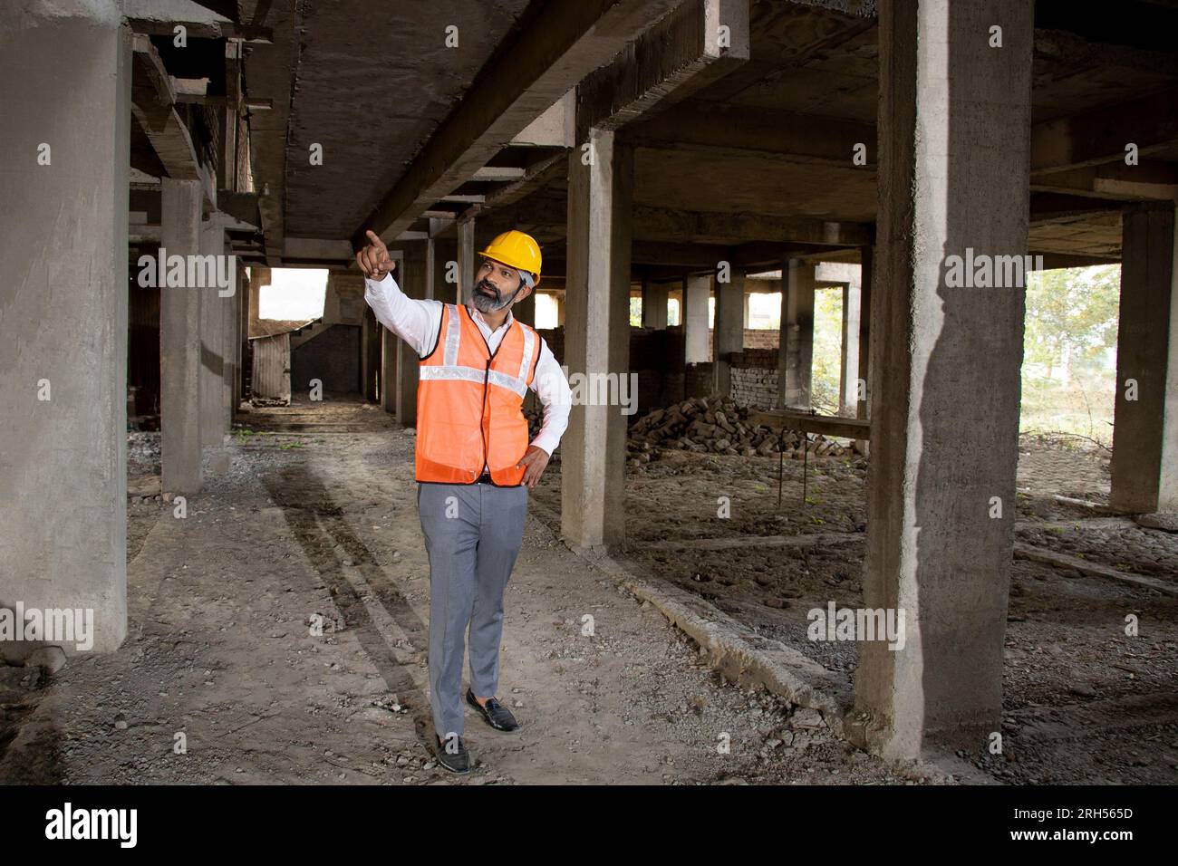 Young Indian male civil engineer or architect wearing helmet and vest ...