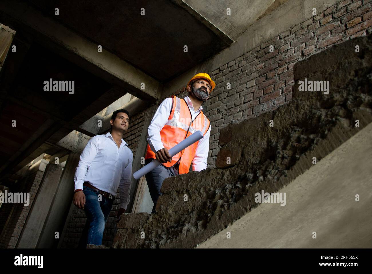 Two Indian male civil engineers or architect wearing helmet and vest ...