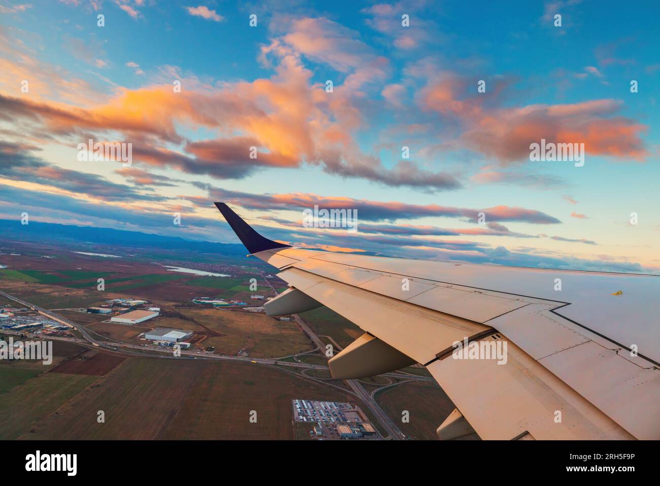 Airplane flight in sunset sky over city and wing of plane. View from ...