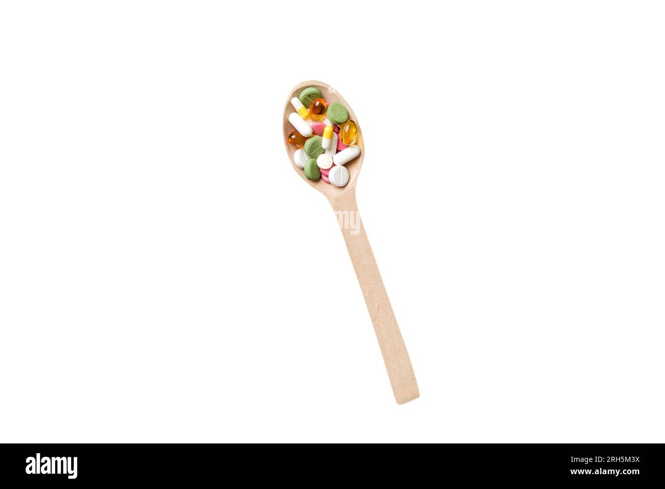 Vitamin capsules in a wooden spoon on a colored background. Pills ...