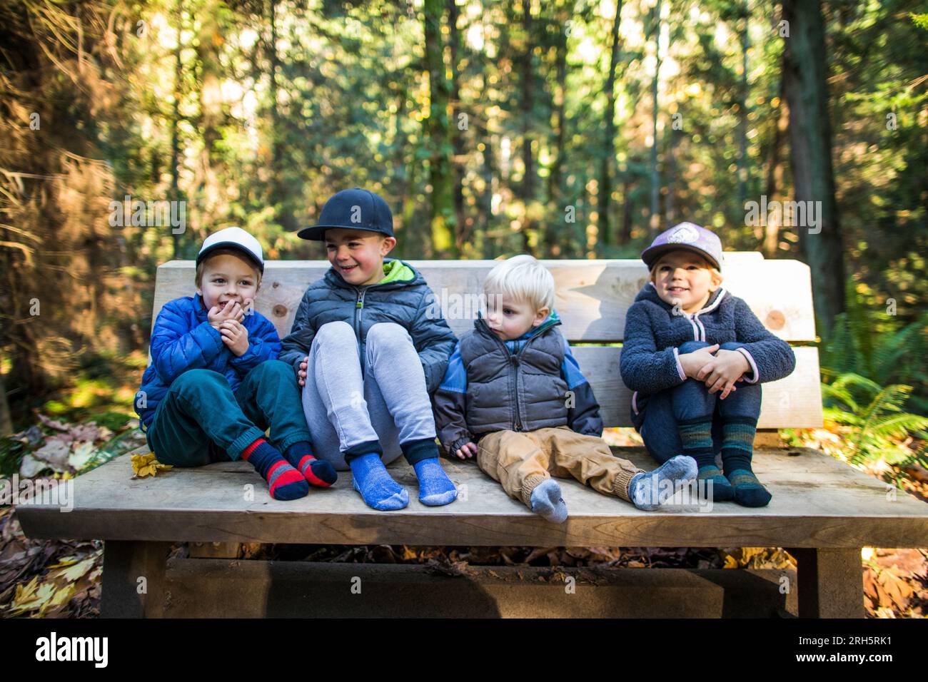 Four young kids sit, rest on wood park bench Stock Photo - Alamy