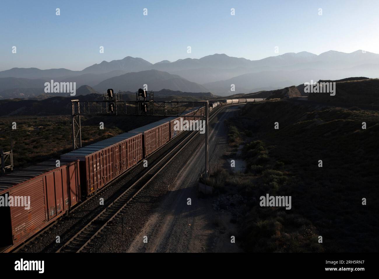 Railroad freight cars pass under a signal bridge in landscape Stock ...