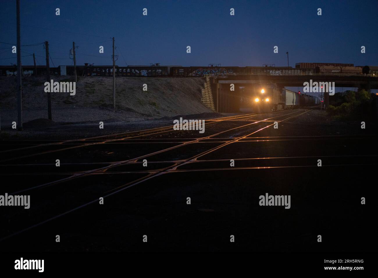 Train headlights approach from under bridge at dusk Stock Photo - Alamy