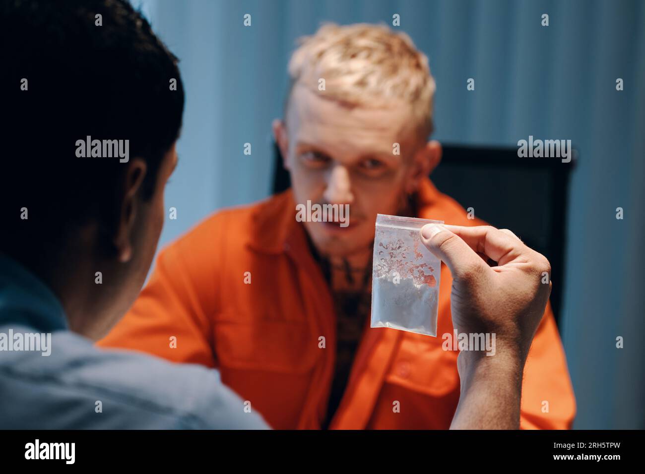 Detective showing criminal small bag with white powder as evidence ...