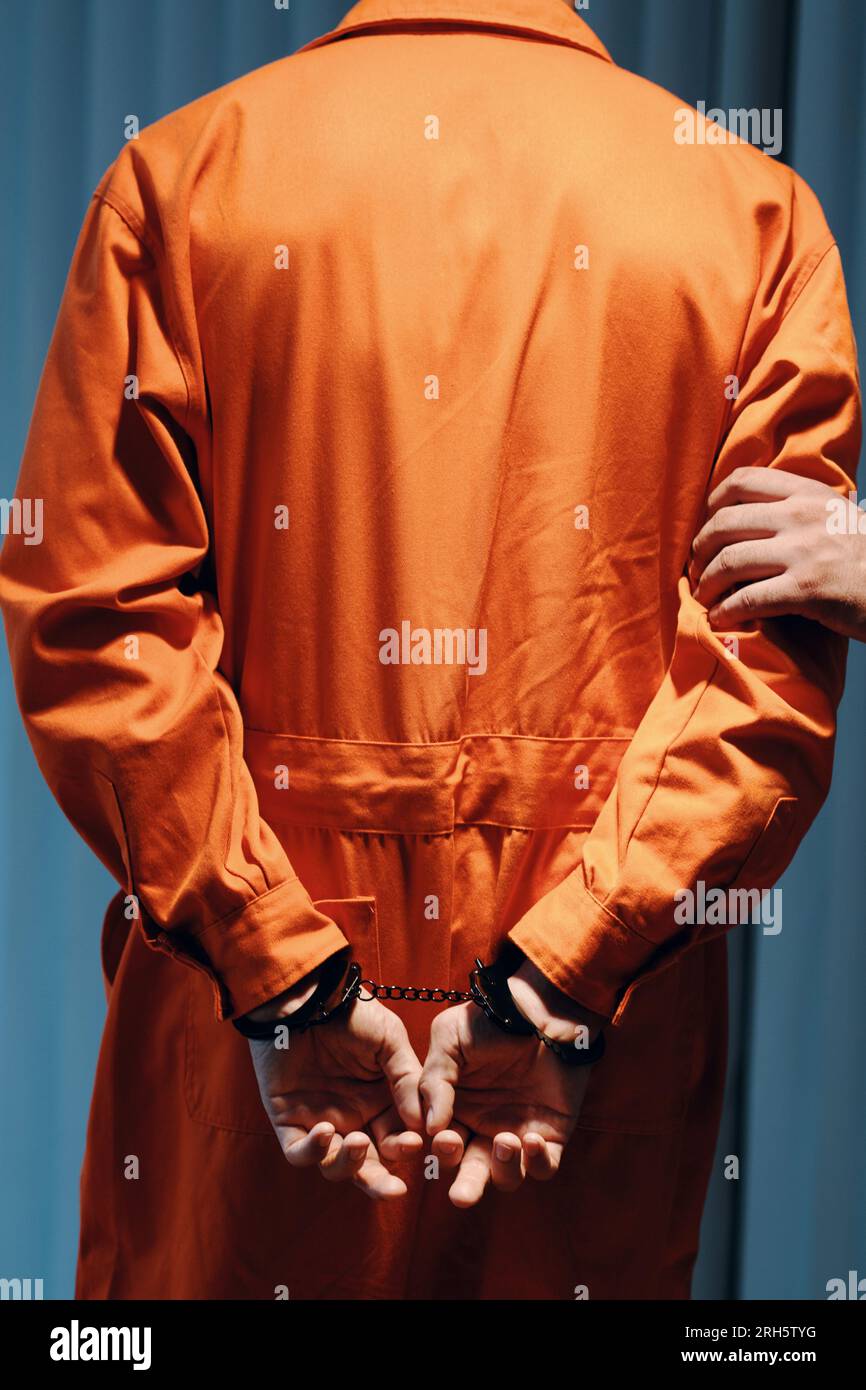 Police officer walking arrested criminal in orange uniform to jail ...