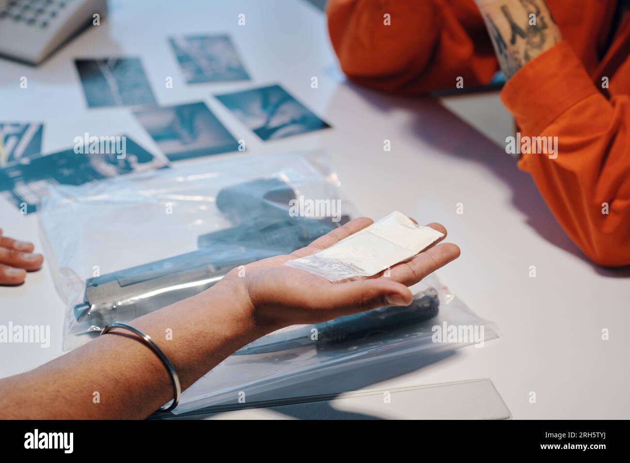 Hand of detective holding small bag of white powder when talking to ...