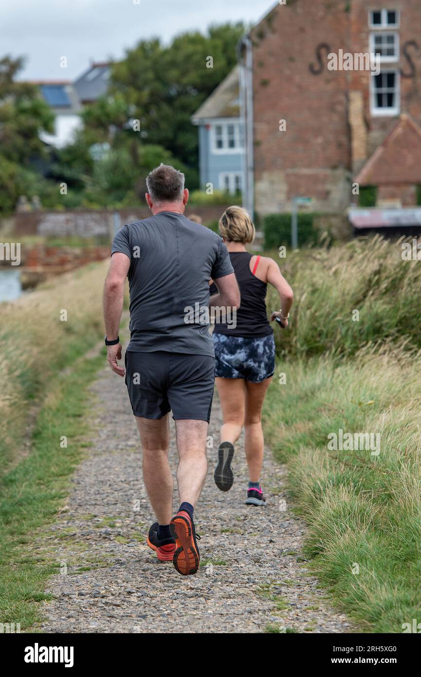 husband and wife couple out for a run along a country track together ...