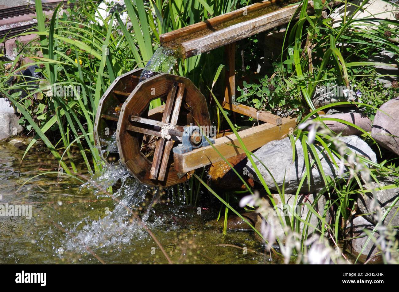 Little Wooden waterwheel with crystal clear water Stock Photo - Alamy