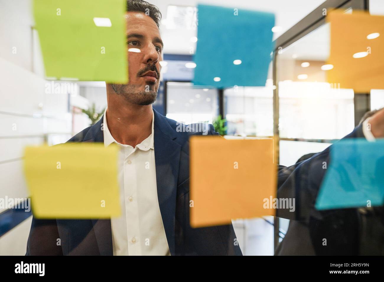 Latin man working inside business office while writing ideas for new ...