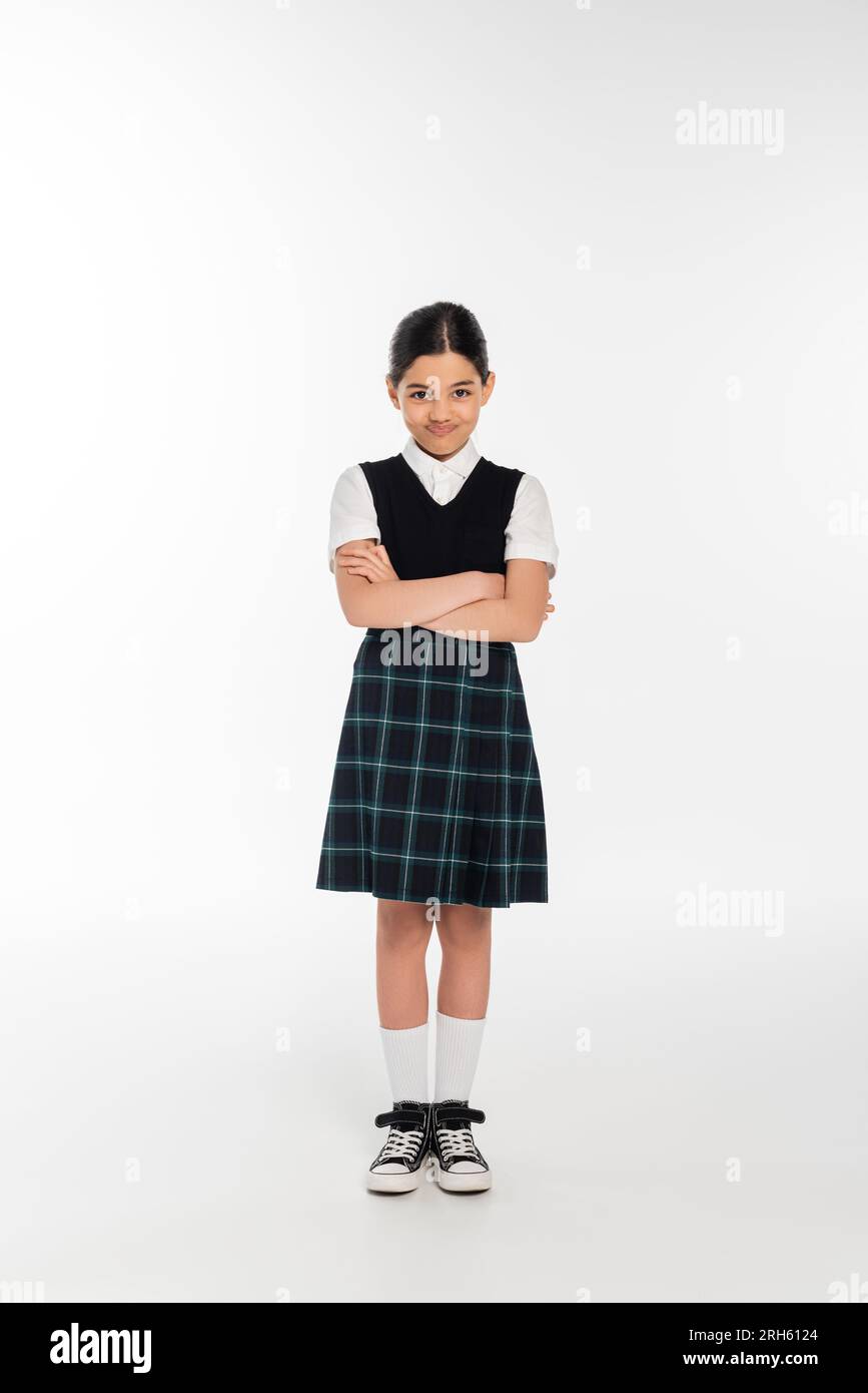 full length, offended schoolkid in uniform looking at camera and ...