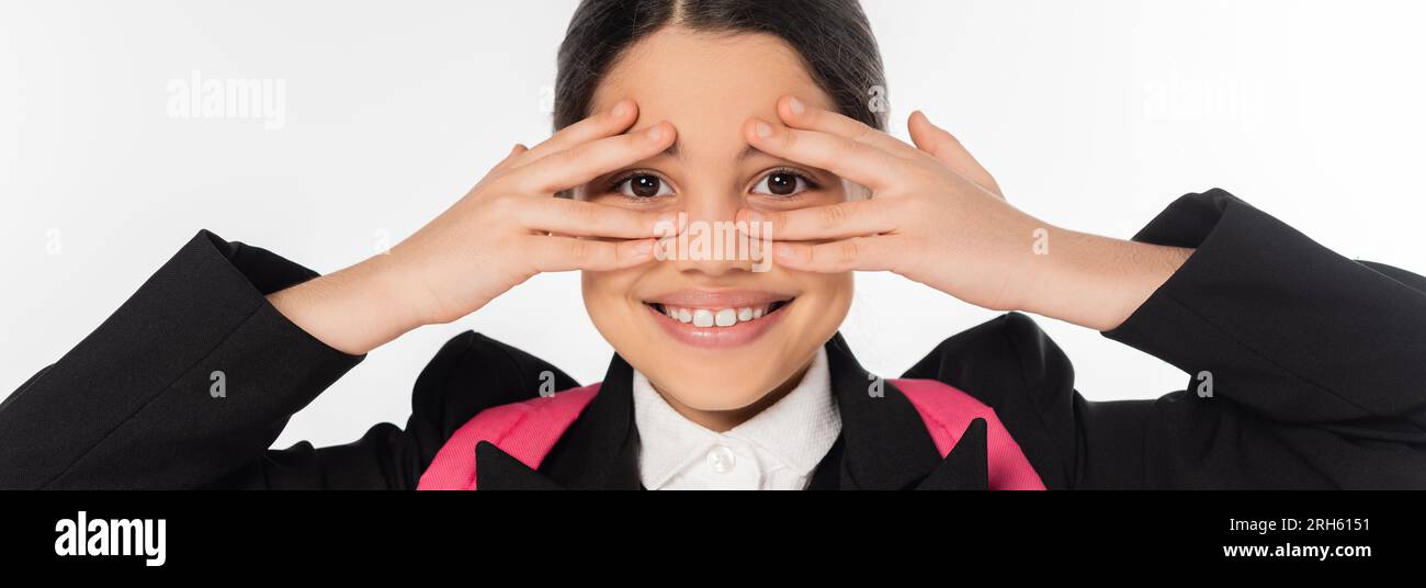 happy schoolgirl covering eyes isolated on white, student in uniform ...