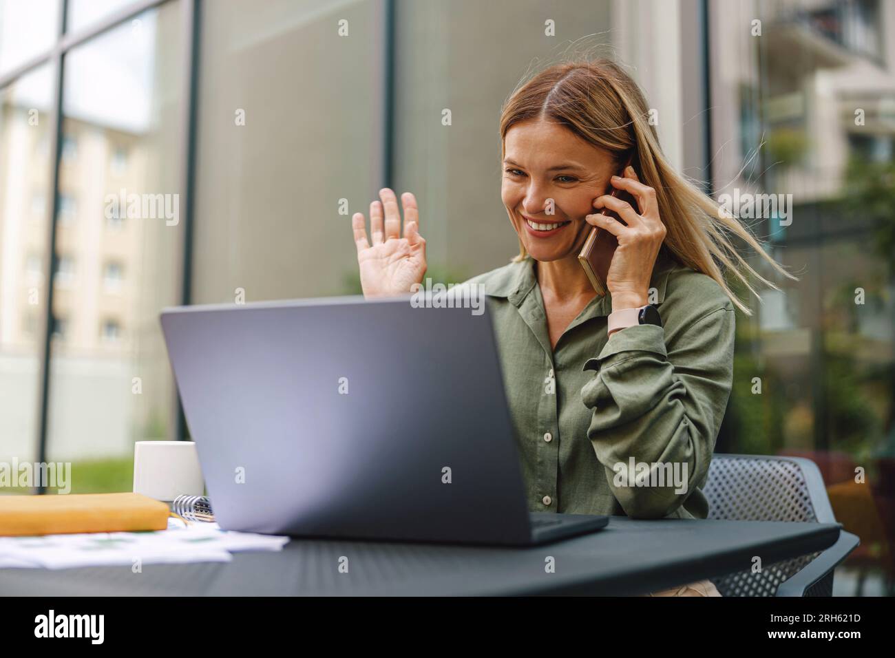 Smiling businesswoman talking with client via video call and waving Hi ...