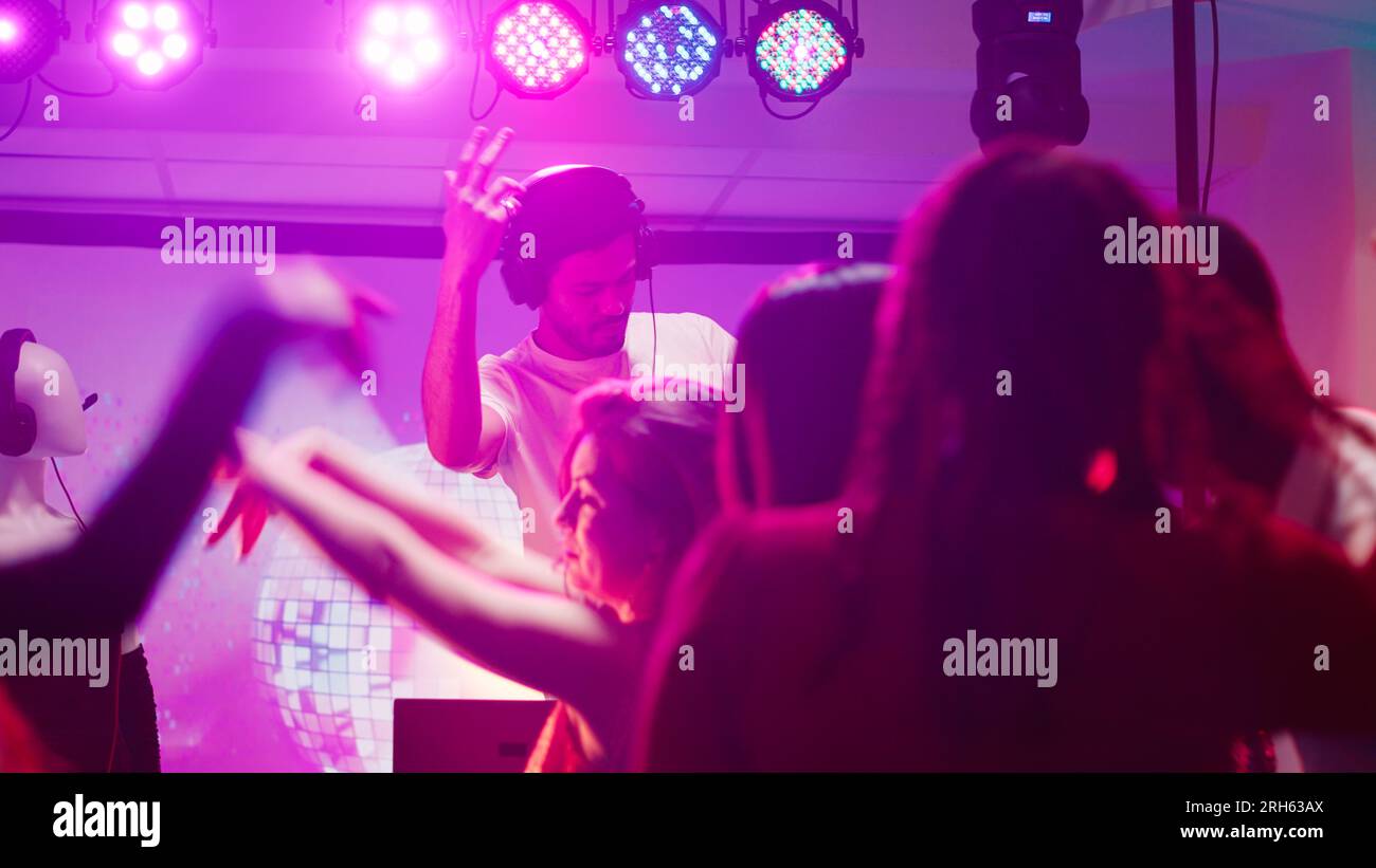 Male DJ partying with people at club, mixing music on audio station to ...