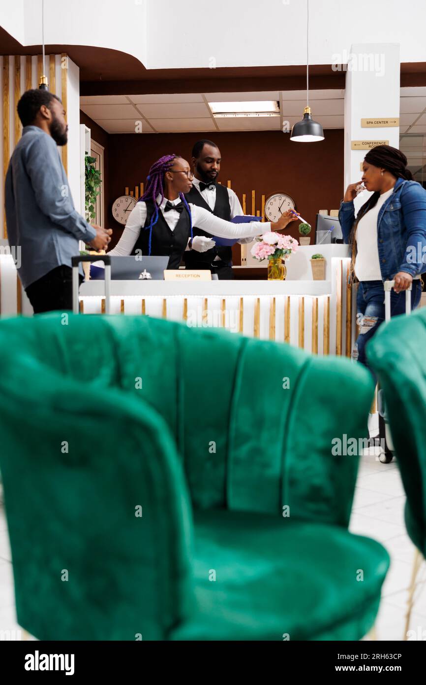 Young African American couple arriving at hotel, standing at reception ...