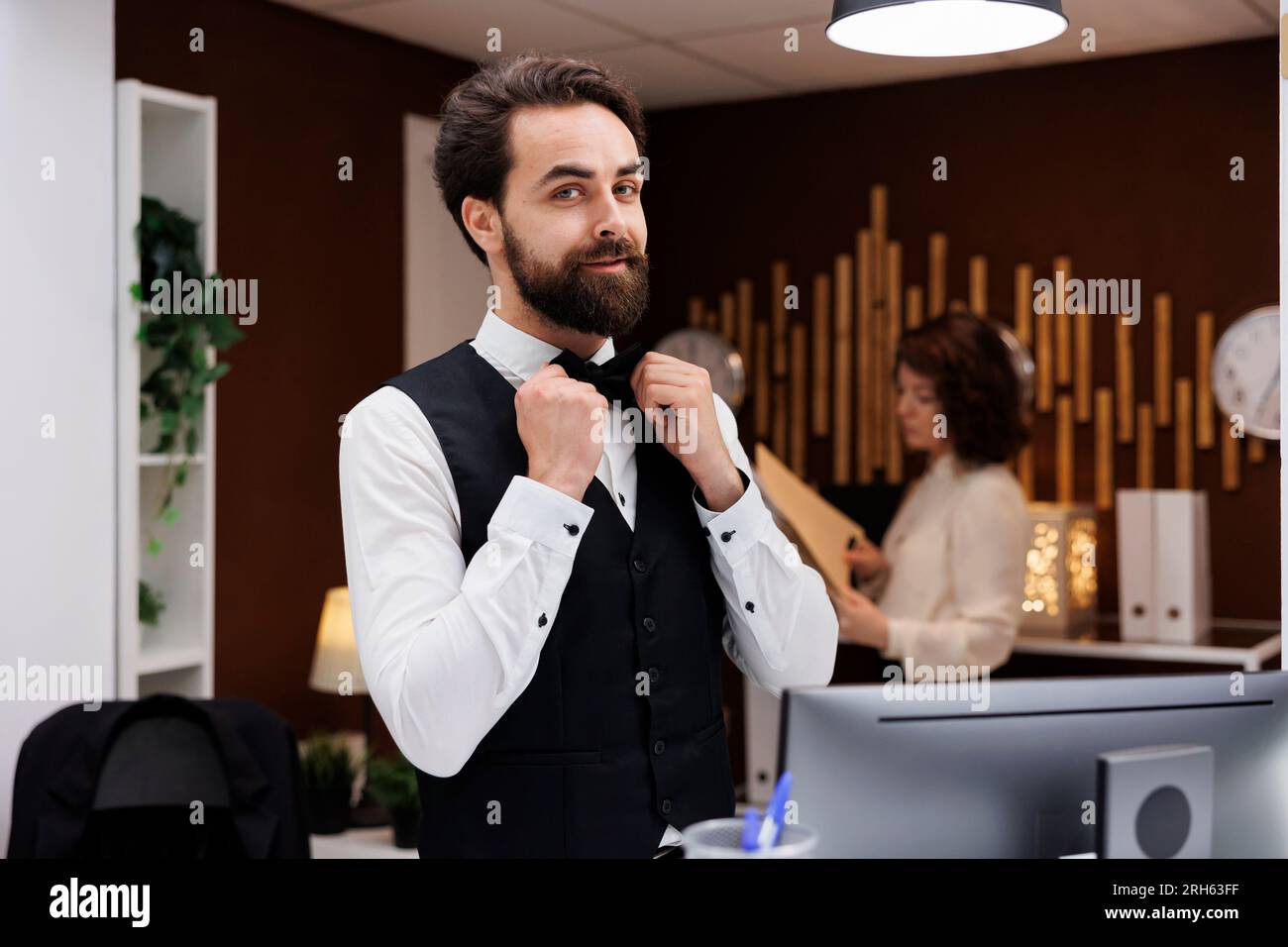 Young worker at hotel reception counter welcoming guests at arrival ...