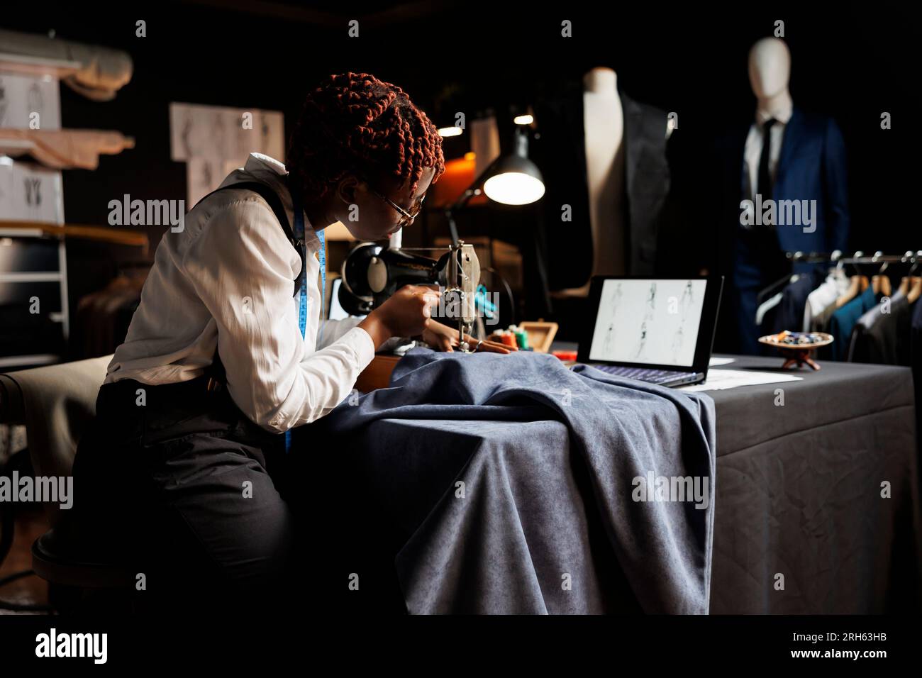 Expert suitmaker cutting piece of fabric with professional sewing ...