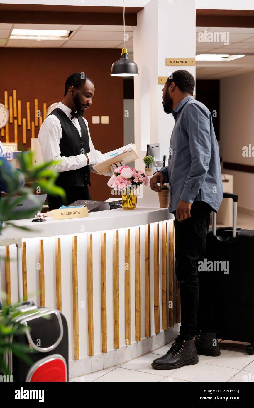 Young African American man front desk agent confirming guest ...