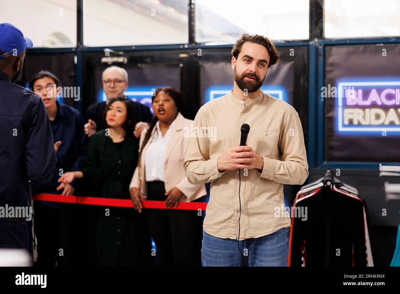 Male television reporter standing in crowded clothing store holding ...