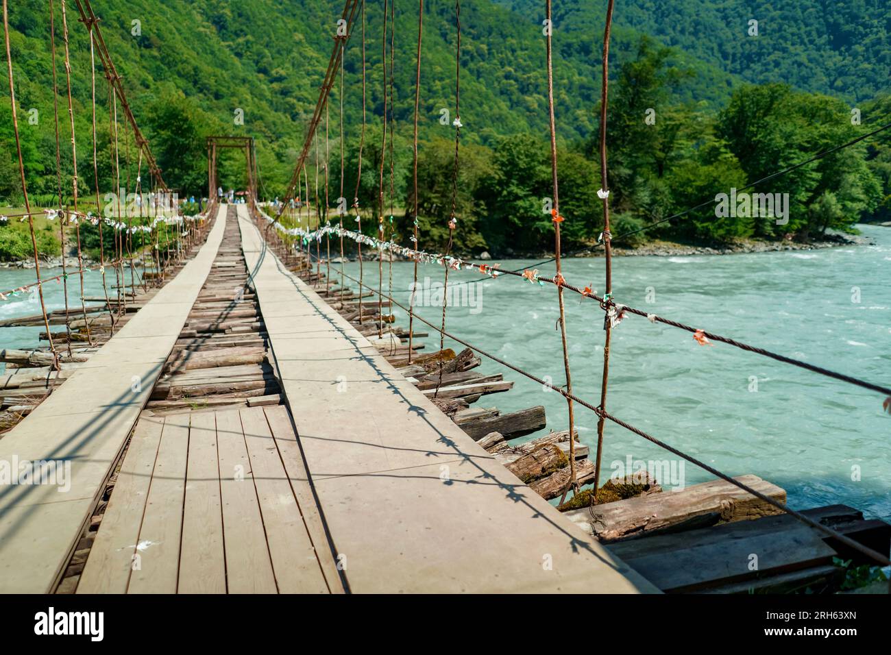 old wooden suspension bridge hanging over mountaing fast river . High ...
