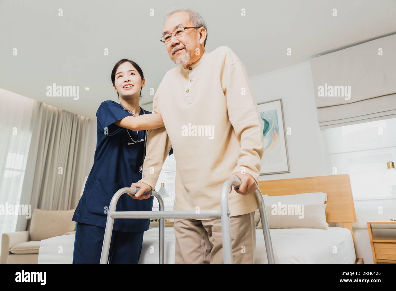 Smiling nurse woman helping senior Asian man to walk around the nursing ...
