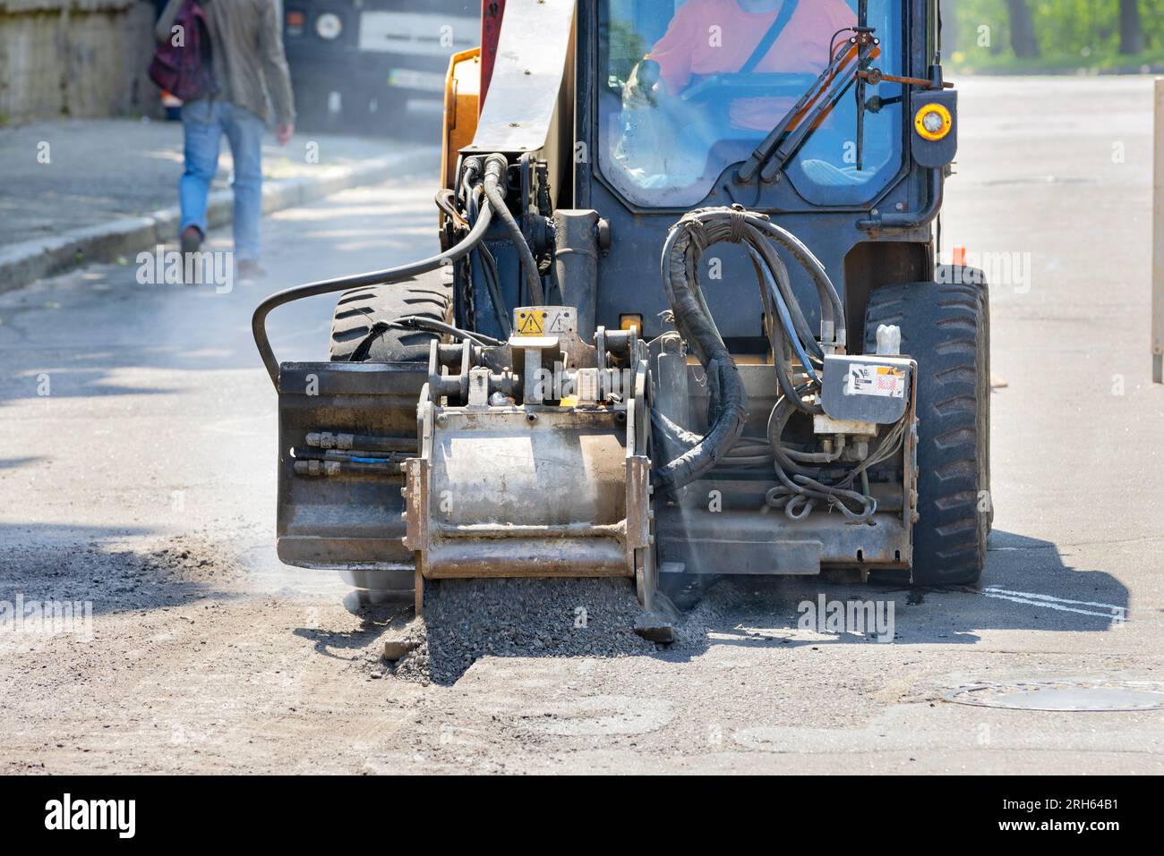 A road construction tractor with a mounted milling machine is repairing ...