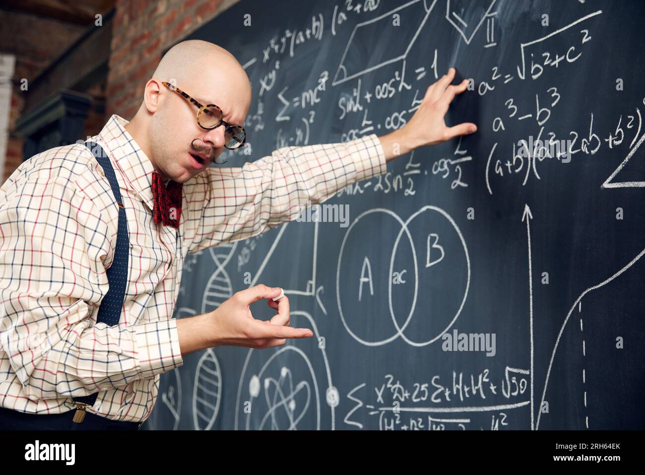 Young man, scientist standing at blackboard with formulas and ...