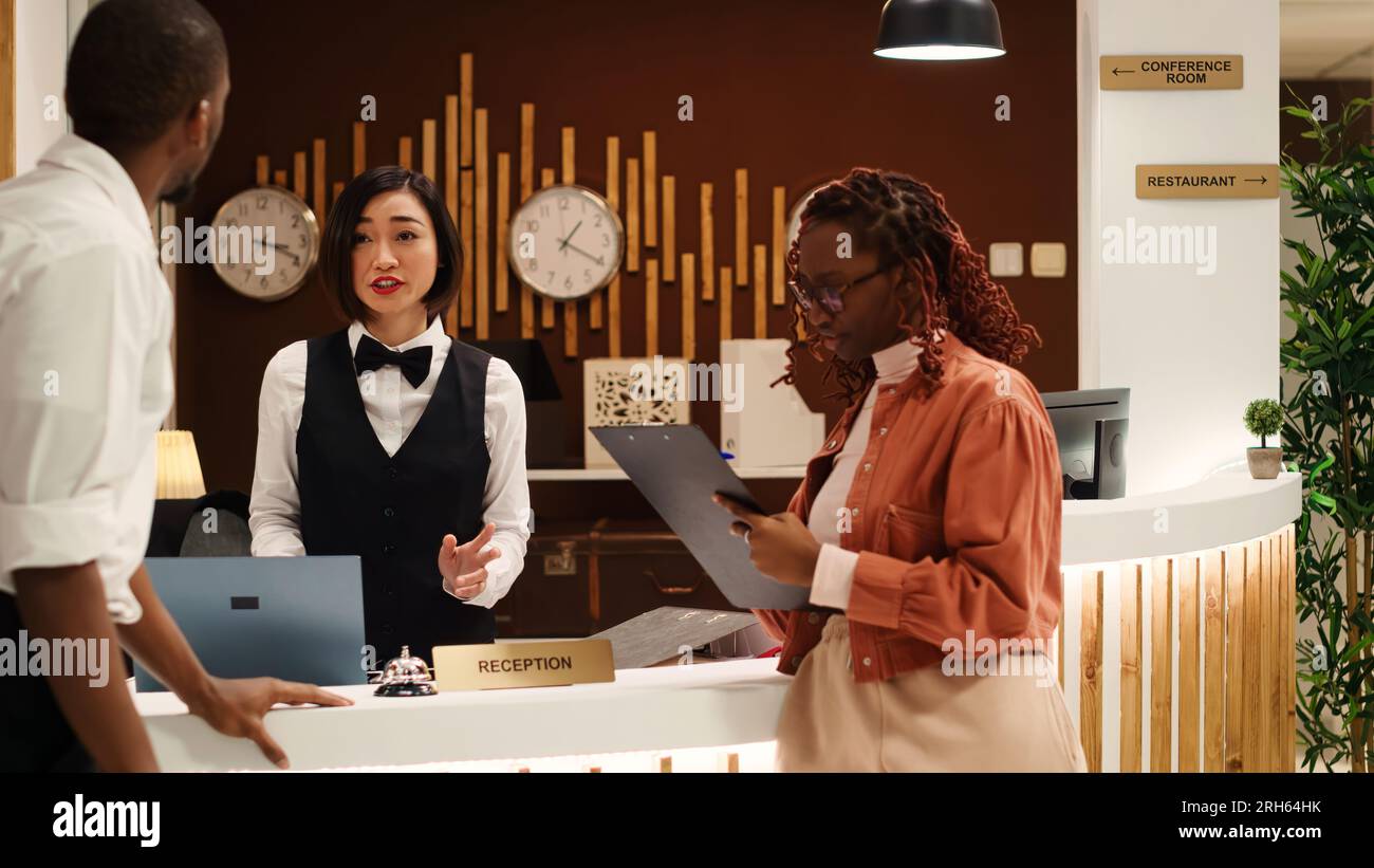 Asian receptionist handing contract on tablet for african american ...