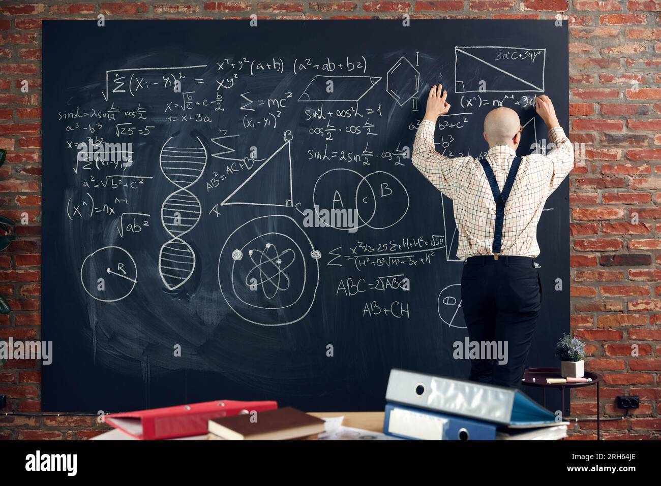Young man, scientist, lecturer standing by blackboard with math and ...