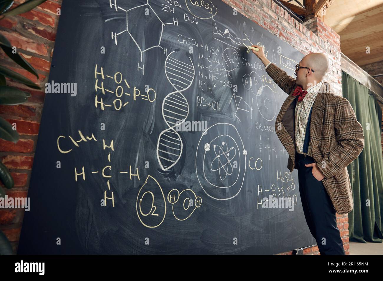 Young bald man, scientist, professor standing by blackboard with ...